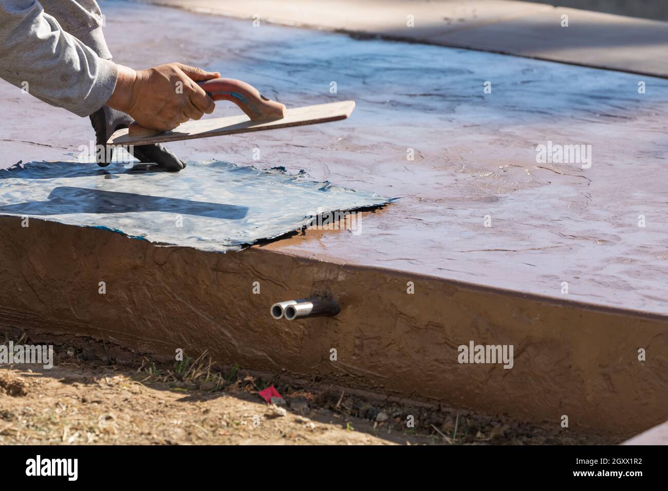 Construction Worker Applying Pressure to Texture Template On Wet Cement ...