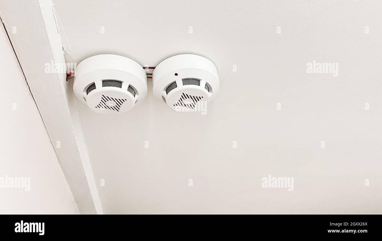 Two smoke detectors are installed on the ceiling in a residential ...