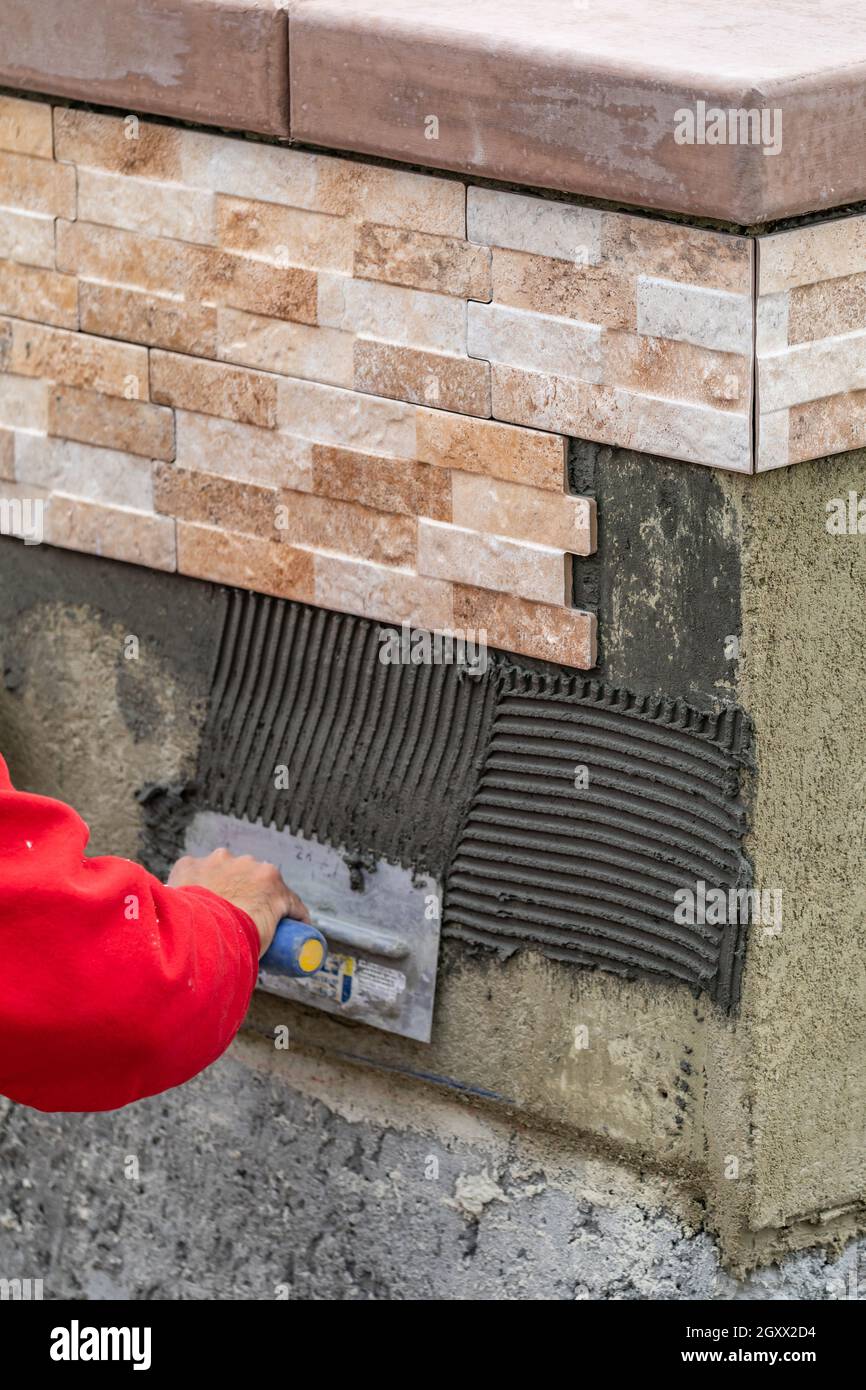 Worker Installing Wall Tile Cement with Trowel and Tile at Construction ...