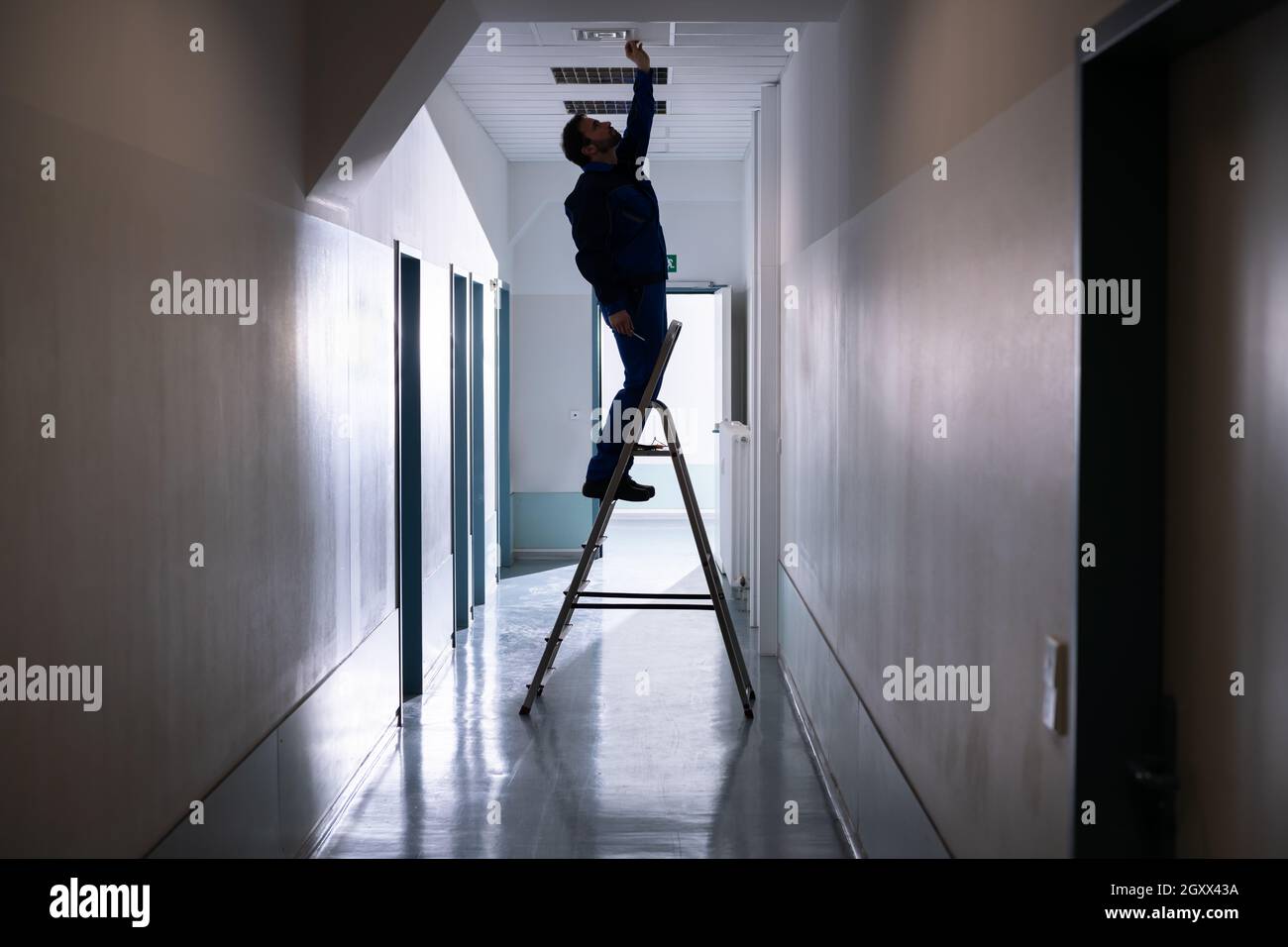 Technician Repairing Ceiling Fixture In Office On Stepladder Stock ...