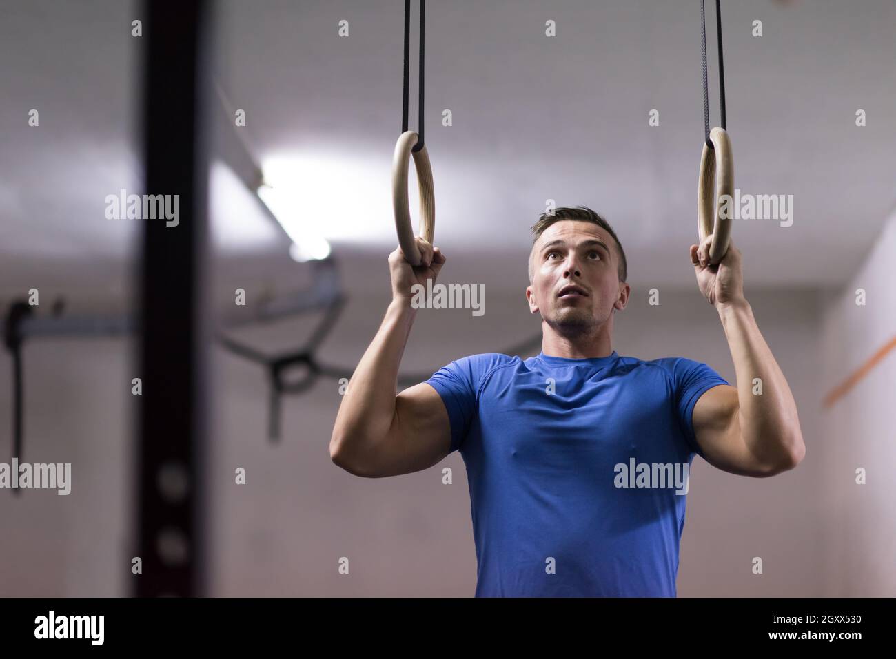Fitness handsome man doing dipping exercise using rings in the gym ...