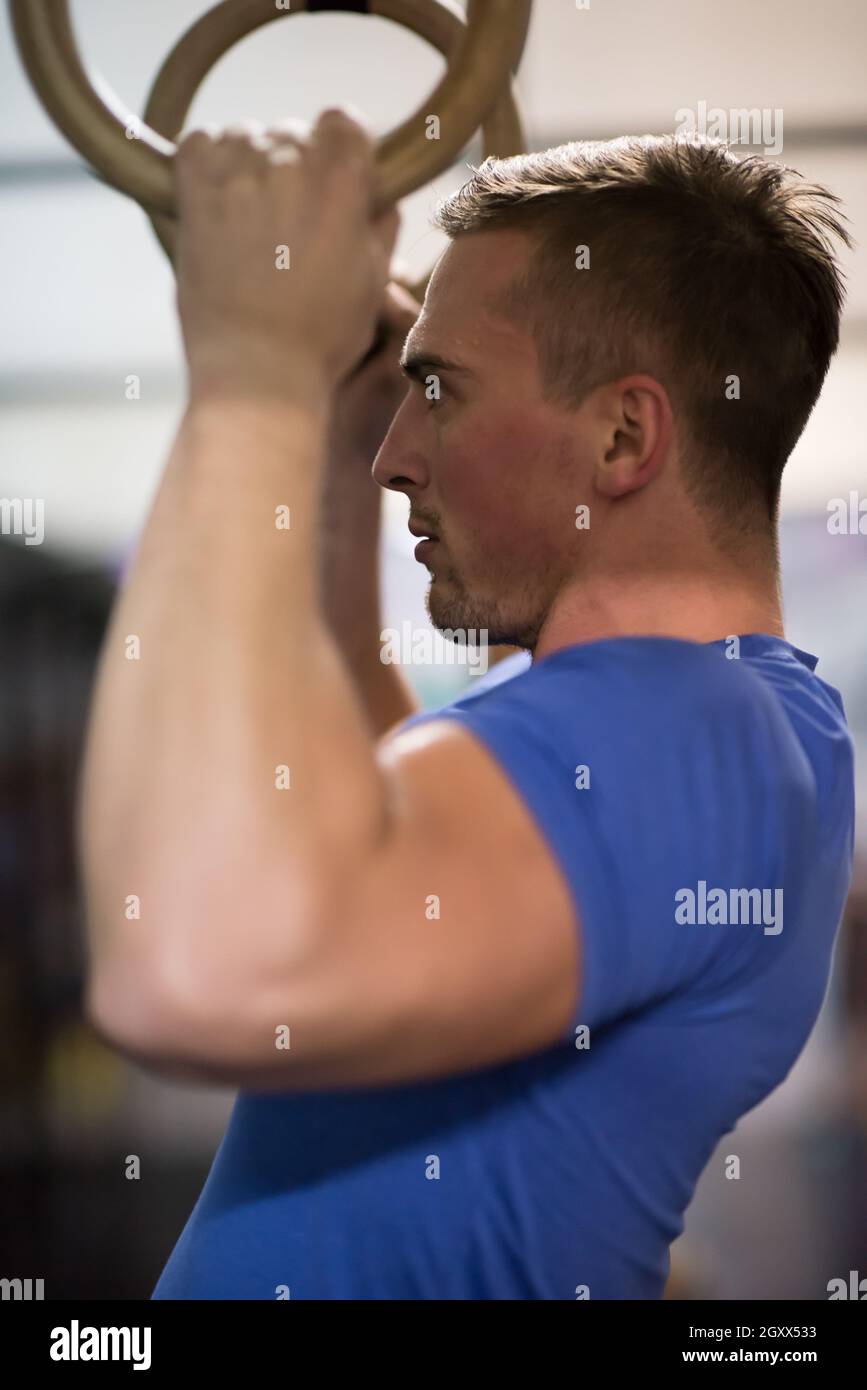 Fitness handsome man doing dipping exercise using rings in the gym ...