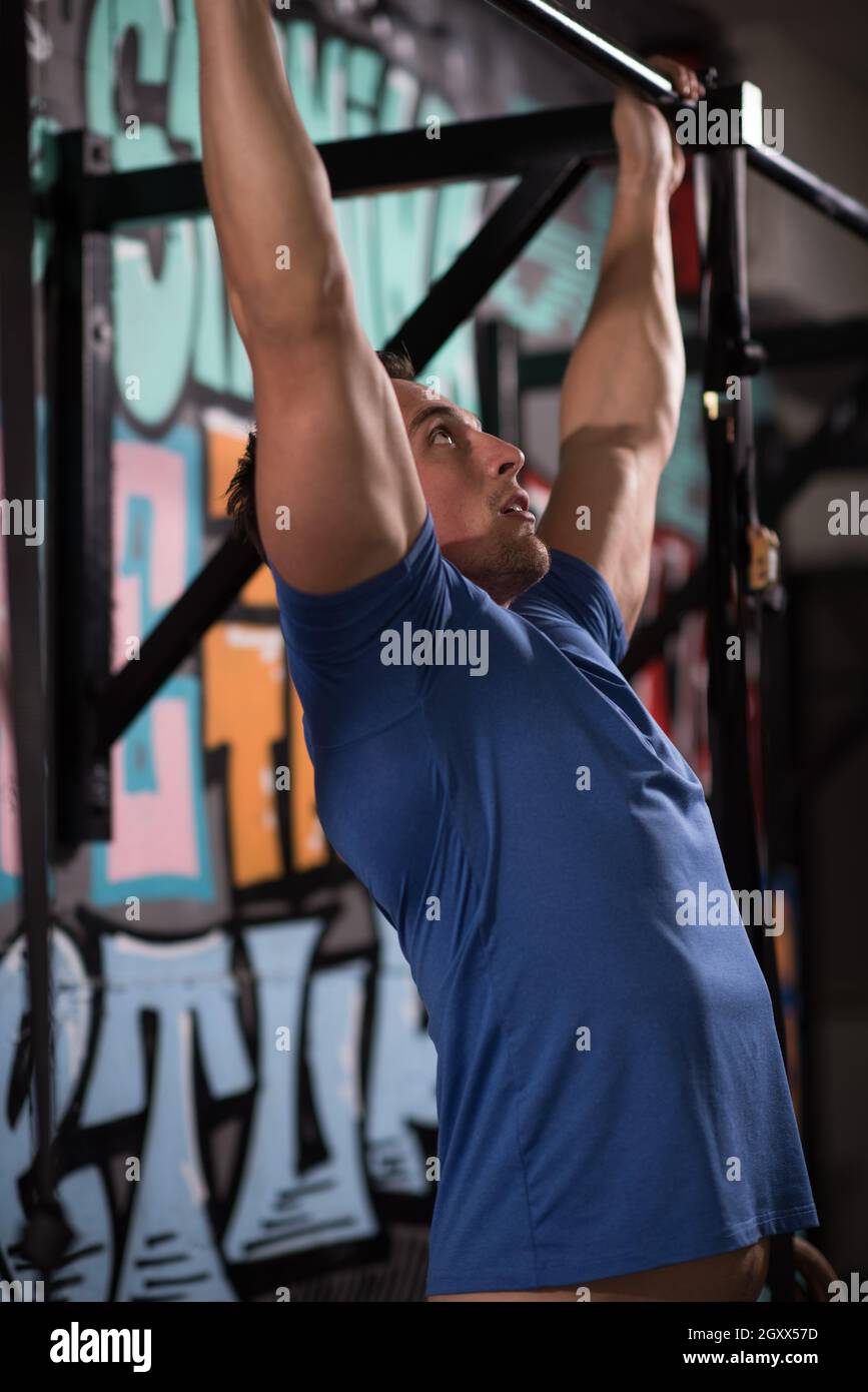strong young man doing pull ups on a bar in a gym Stock Photo - Alamy