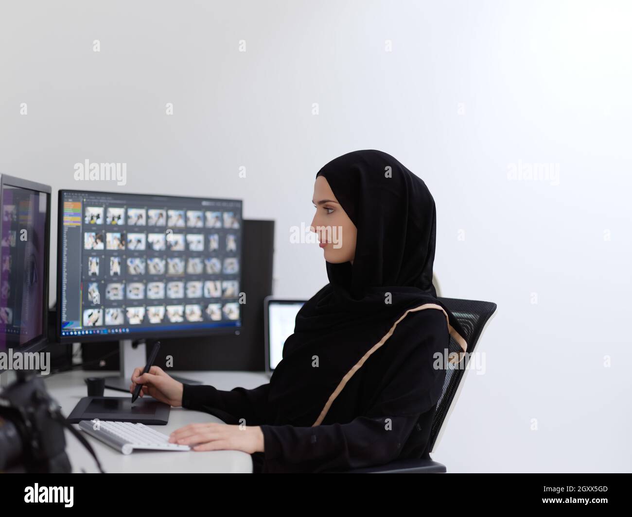Muslim female graphic designer working on computer using graphic tablet ...