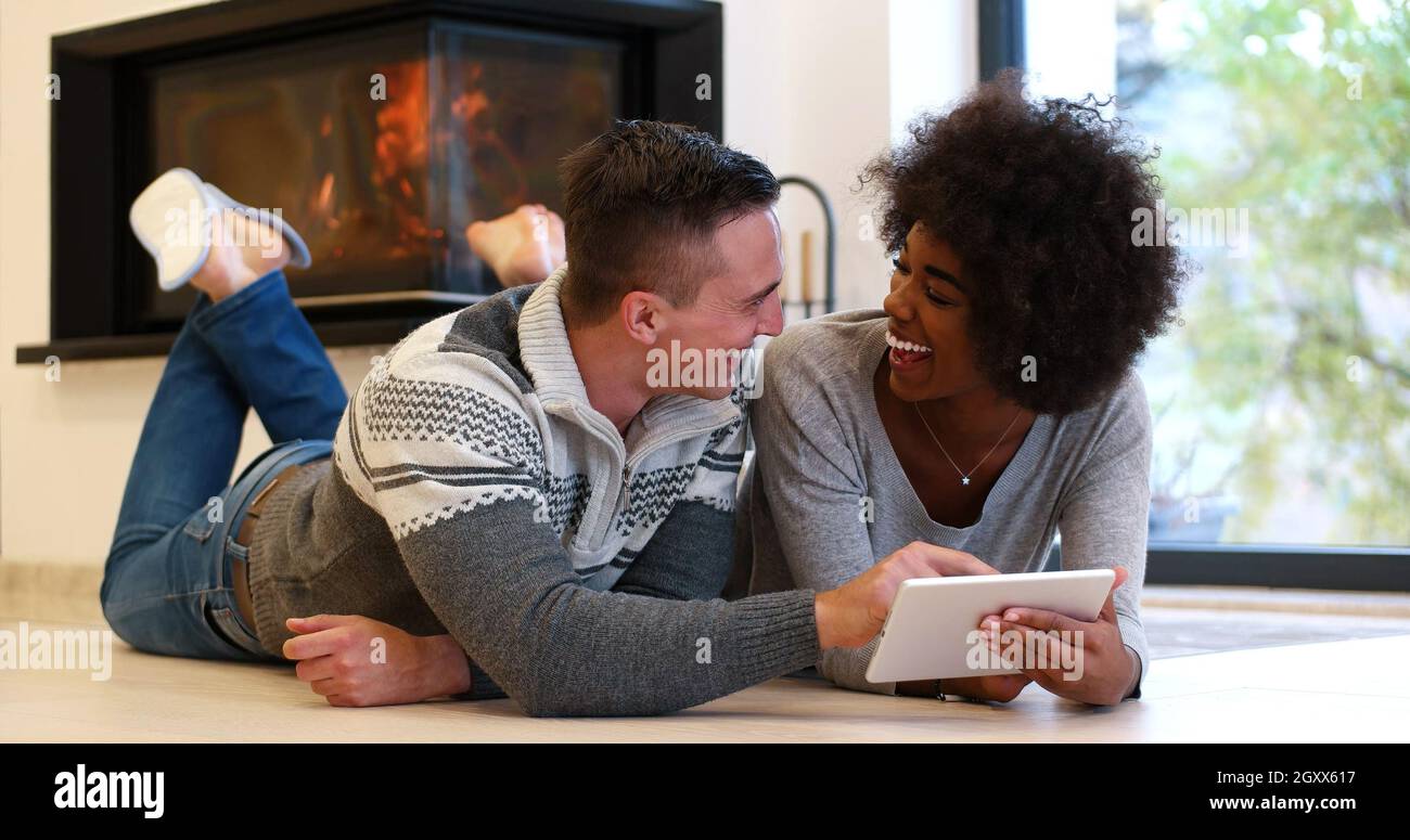 beautiful young multiethnic couple using tablet computer on the floor ...