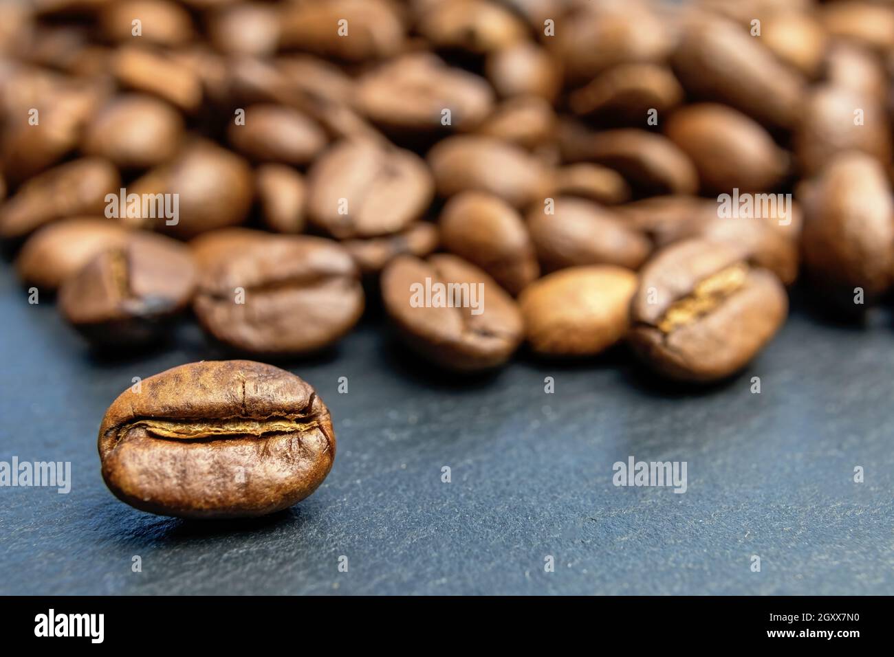 Closeup view of coffee bean lying in front of heap of coffee beans ...