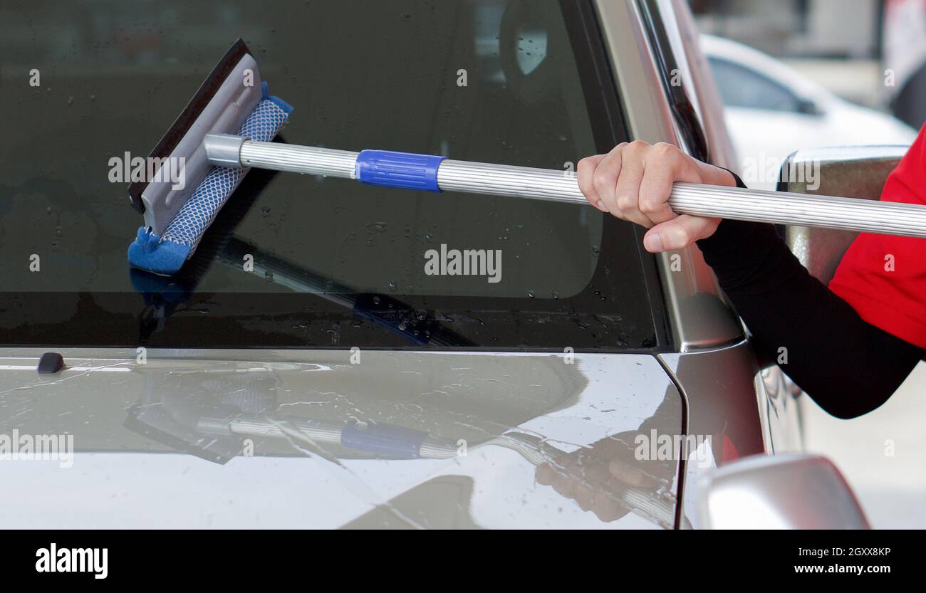 Gas station worker cleaning the car windshield with window squeegee ...