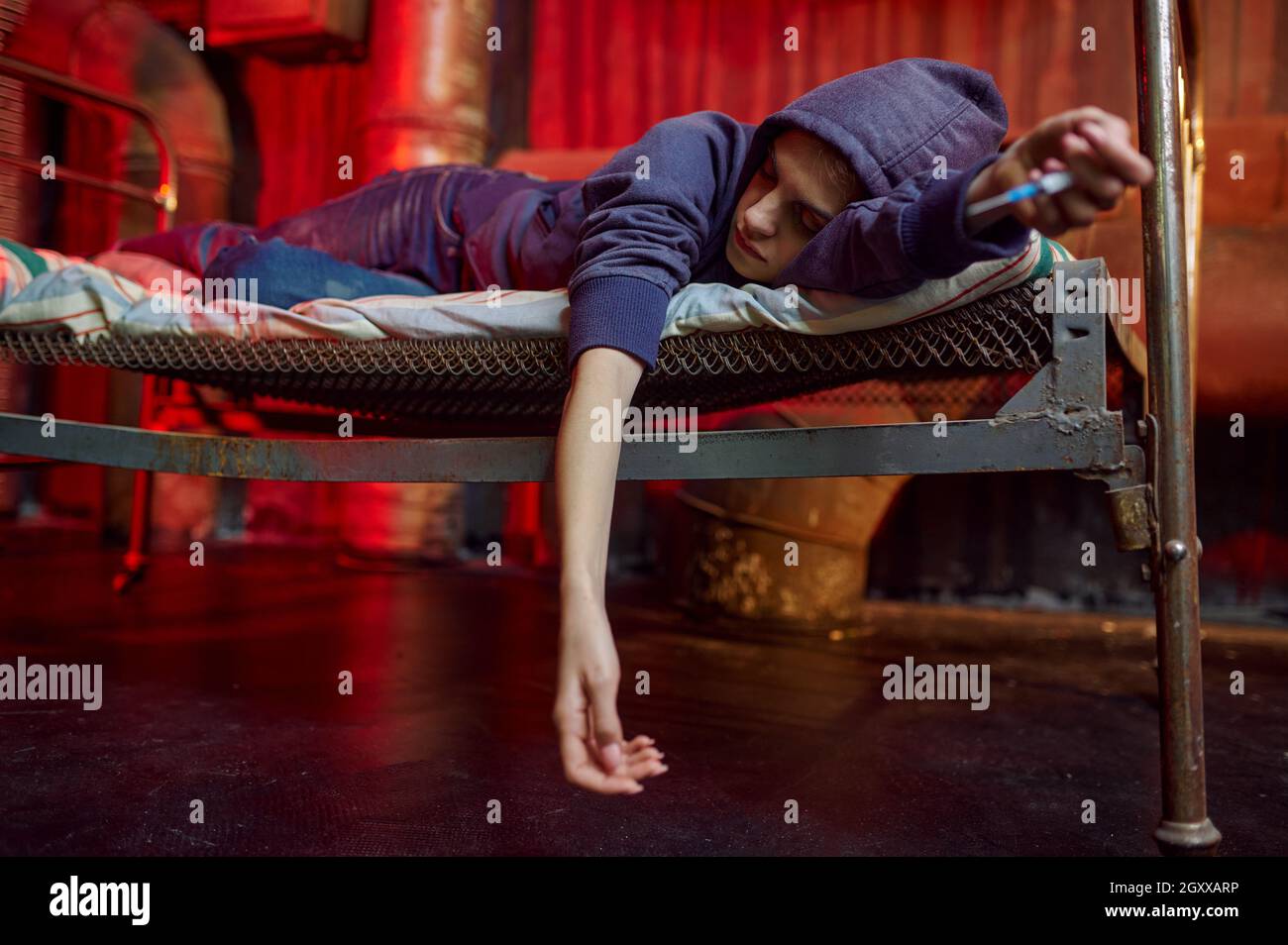 Drug addict woman sleeps on bed in den, shebang interior on background ...