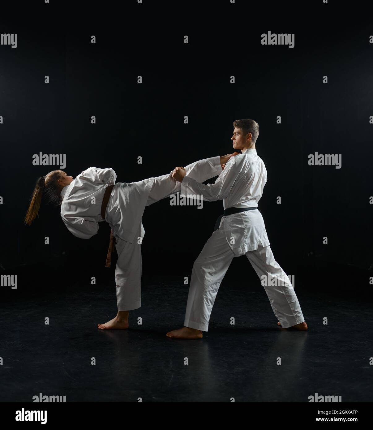 Female karate fighter on training with male master, white kimono, dark ...