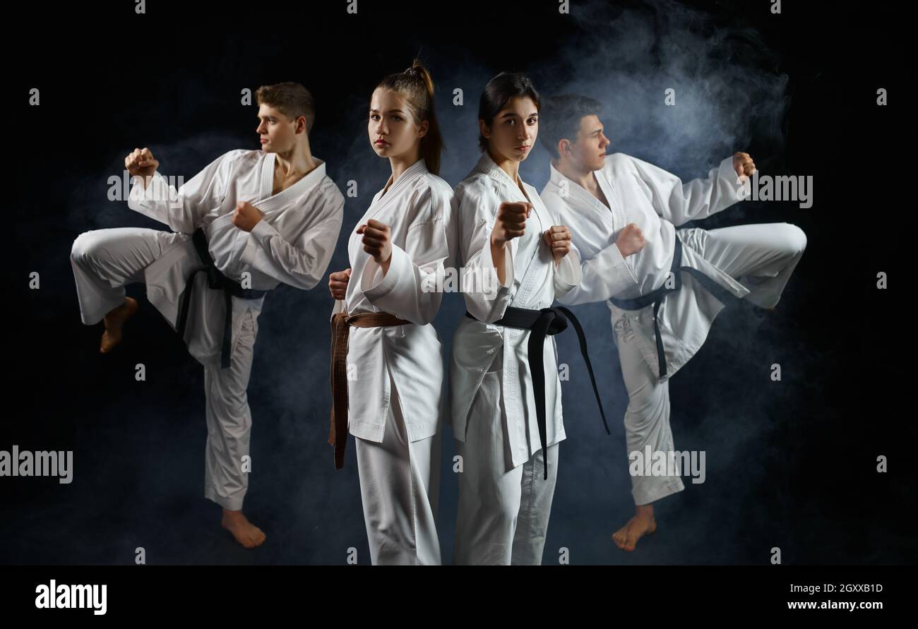 Four karate fighters in white kimono, group training, dark smoky ...