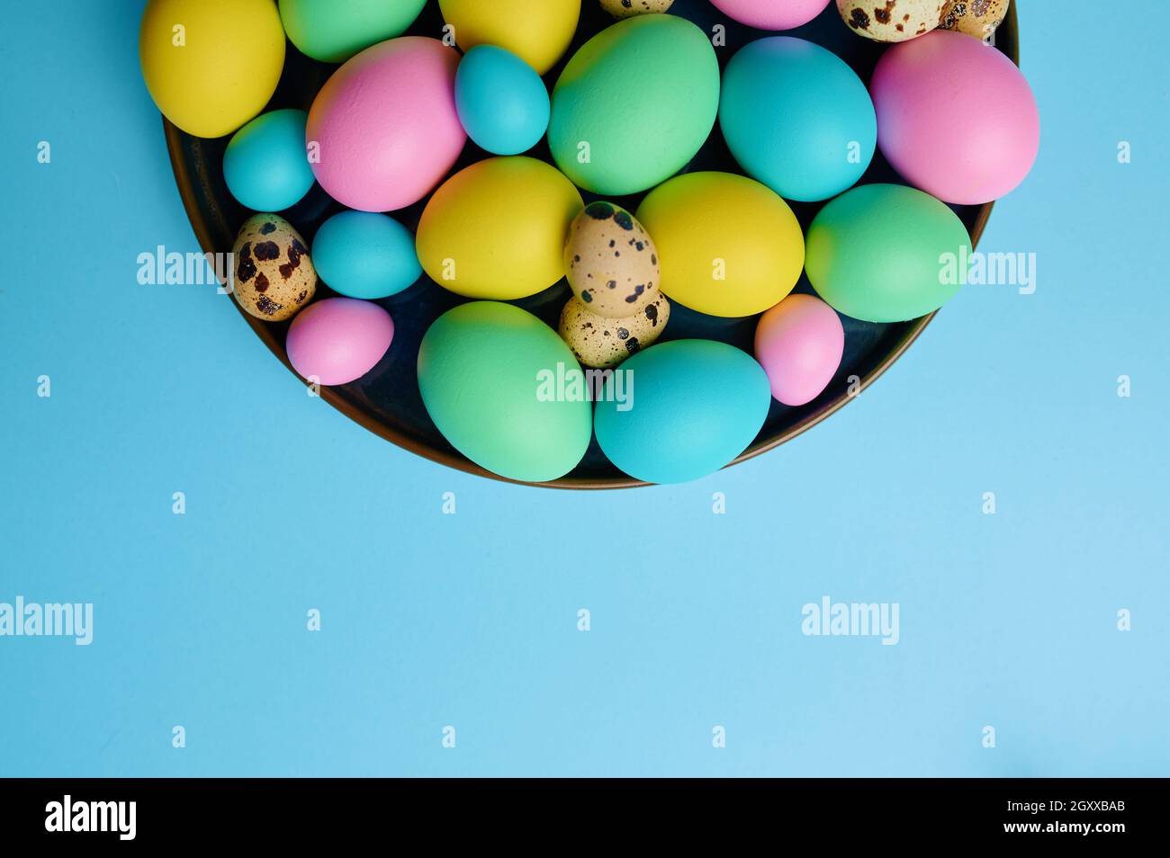 Colorful easter eggs in bowl on blue background, top view. Paschal food ...