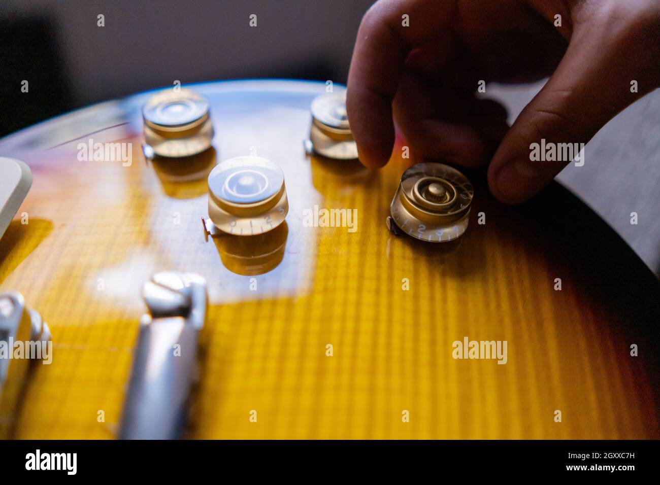 Hand touching the volume controls of classic yellow electric guitar ...