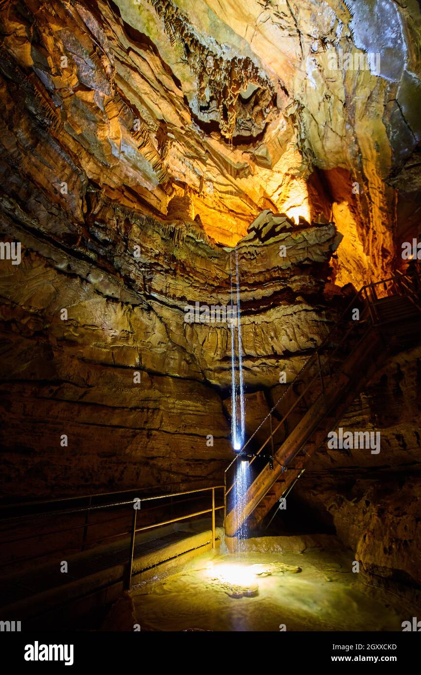 Tall dripping water into large underground cave by path and staircase ...