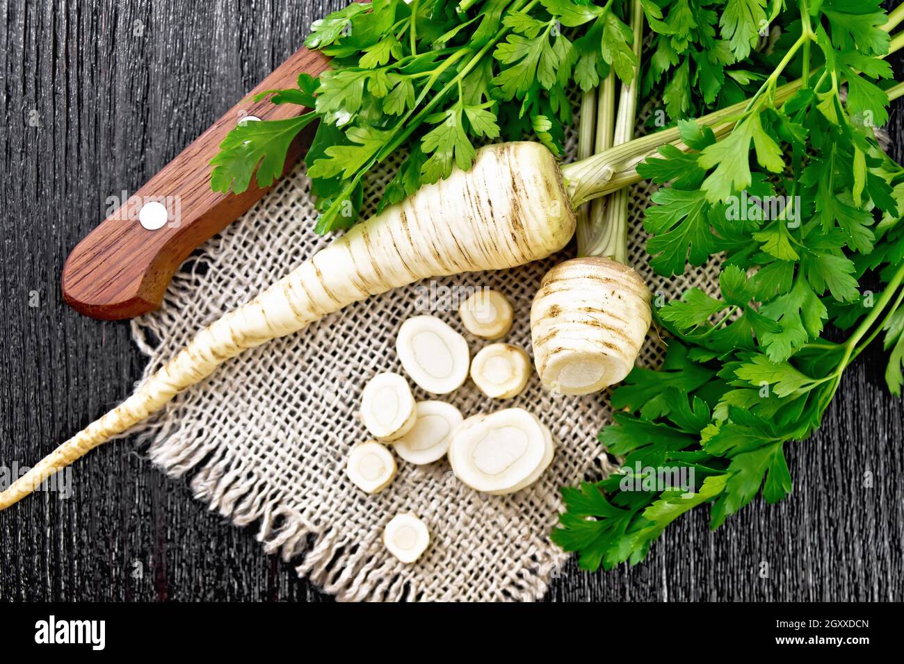 Parsley roots whole and chopped with green tops on a burlap napkin and ...