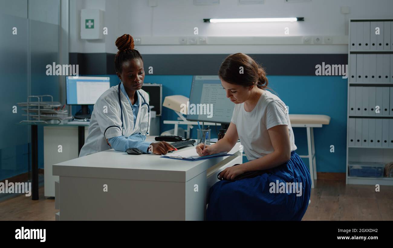Caucasian patient signing checkup document for healthcare system after ...