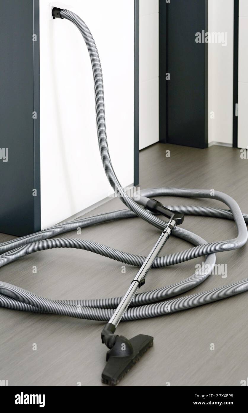 Long central vacuum cleaner hose laid on the grey floor in the room ...