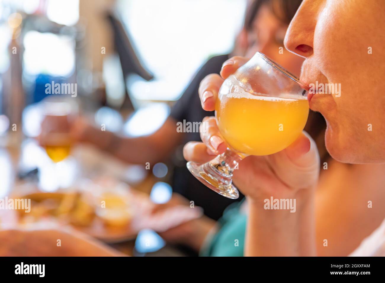 Female Sipping Glass of Micro Brew Beer At Bar With Friends Stock Photo ...
