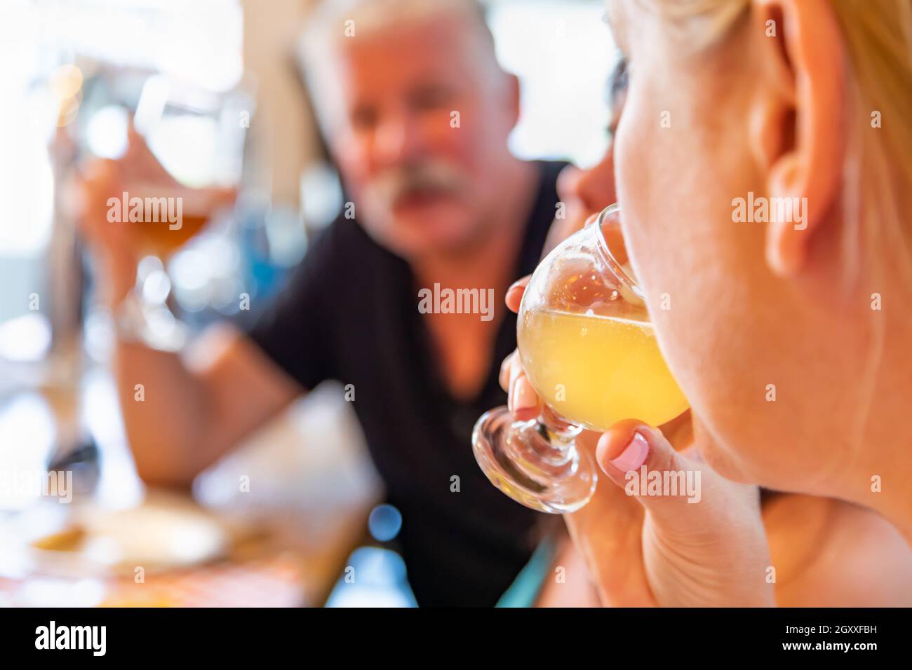 Female Sipping Glass of Micro Brew Beer At Bar With Friends Stock Photo ...