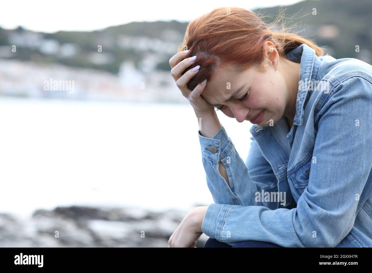 Sad casual woman complaining alone crying on the beach with bad weather ...