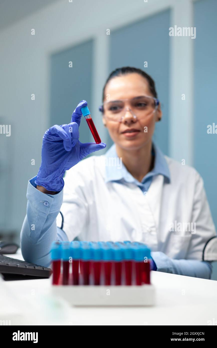 Scientist doctor woman analyzing transparent vacutainer with blood ...