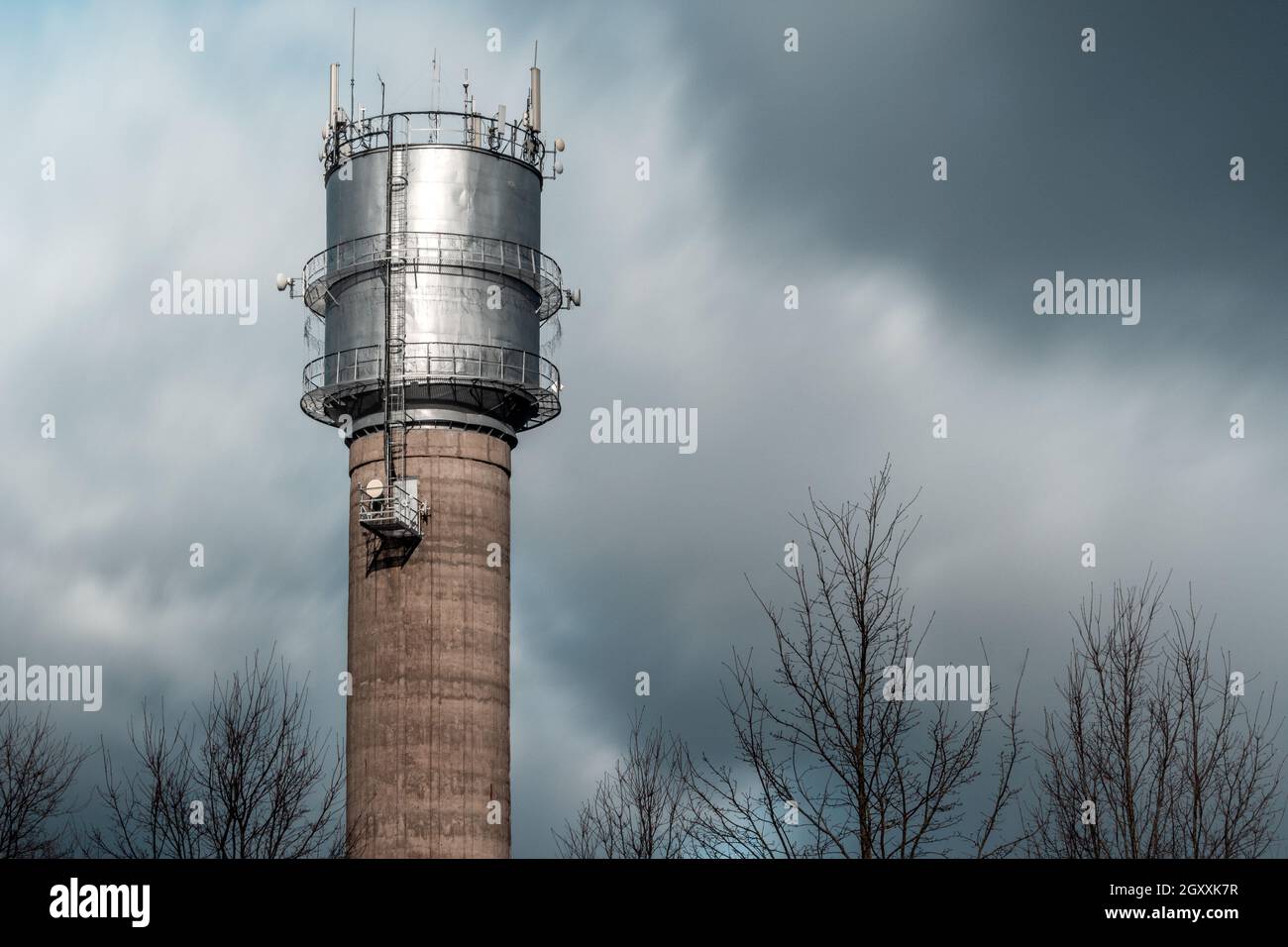 Water tower with communication antennas under stormy sky with dark rain ...