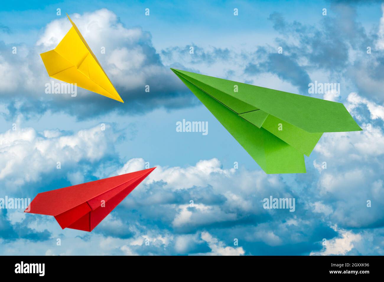 Three colorful paper planes flying in a cloudy sky. Travel concept ...