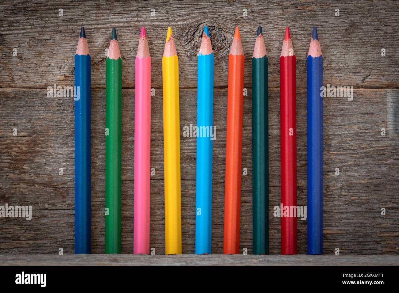 Color pencls standing in a row on wooden shelf Stock Photo - Alamy