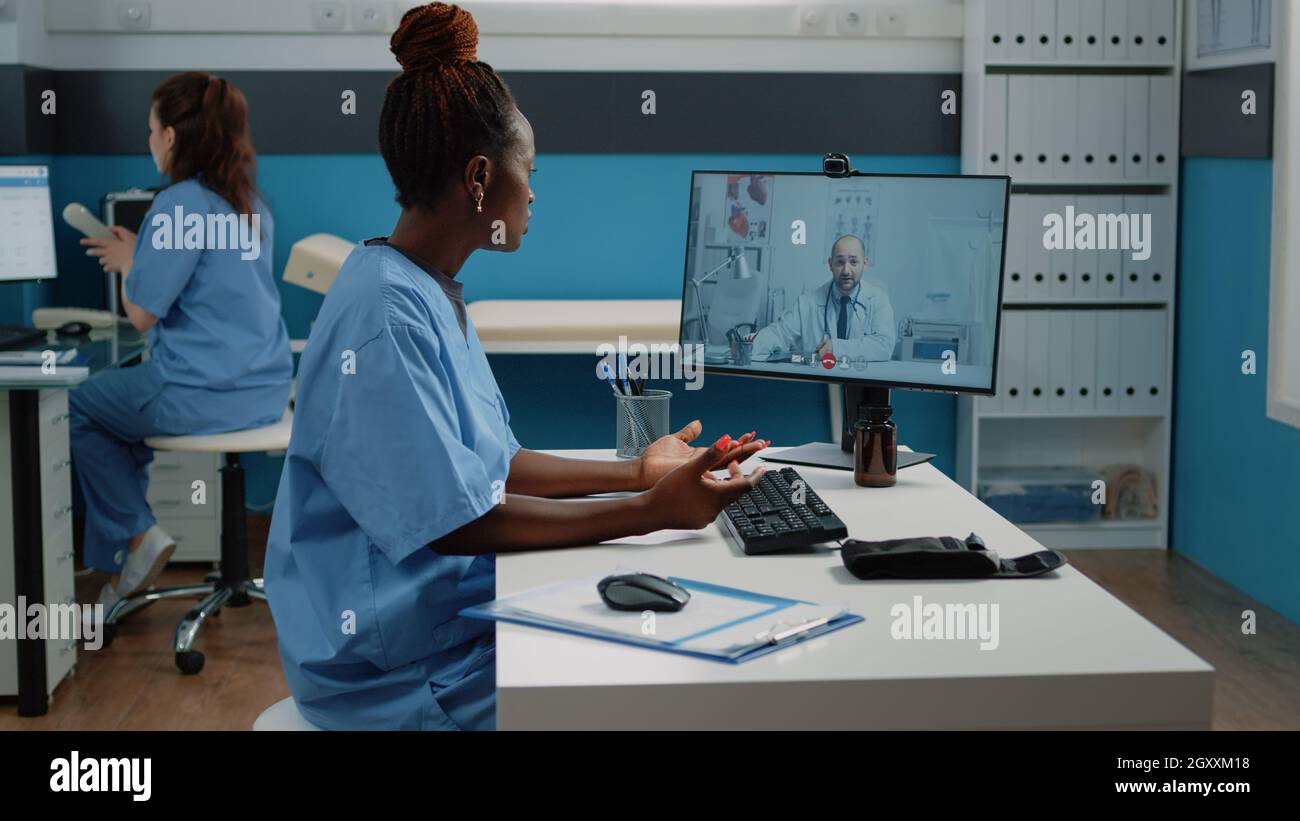 Nurse talking to doctor on video call connection in cabinet. Medical ...
