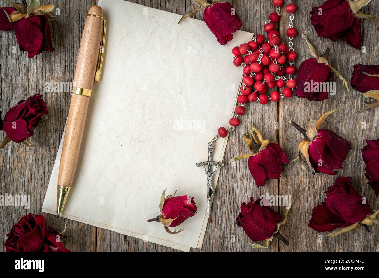 Dry roses, catholic rosary and blank letter on wooden background ...