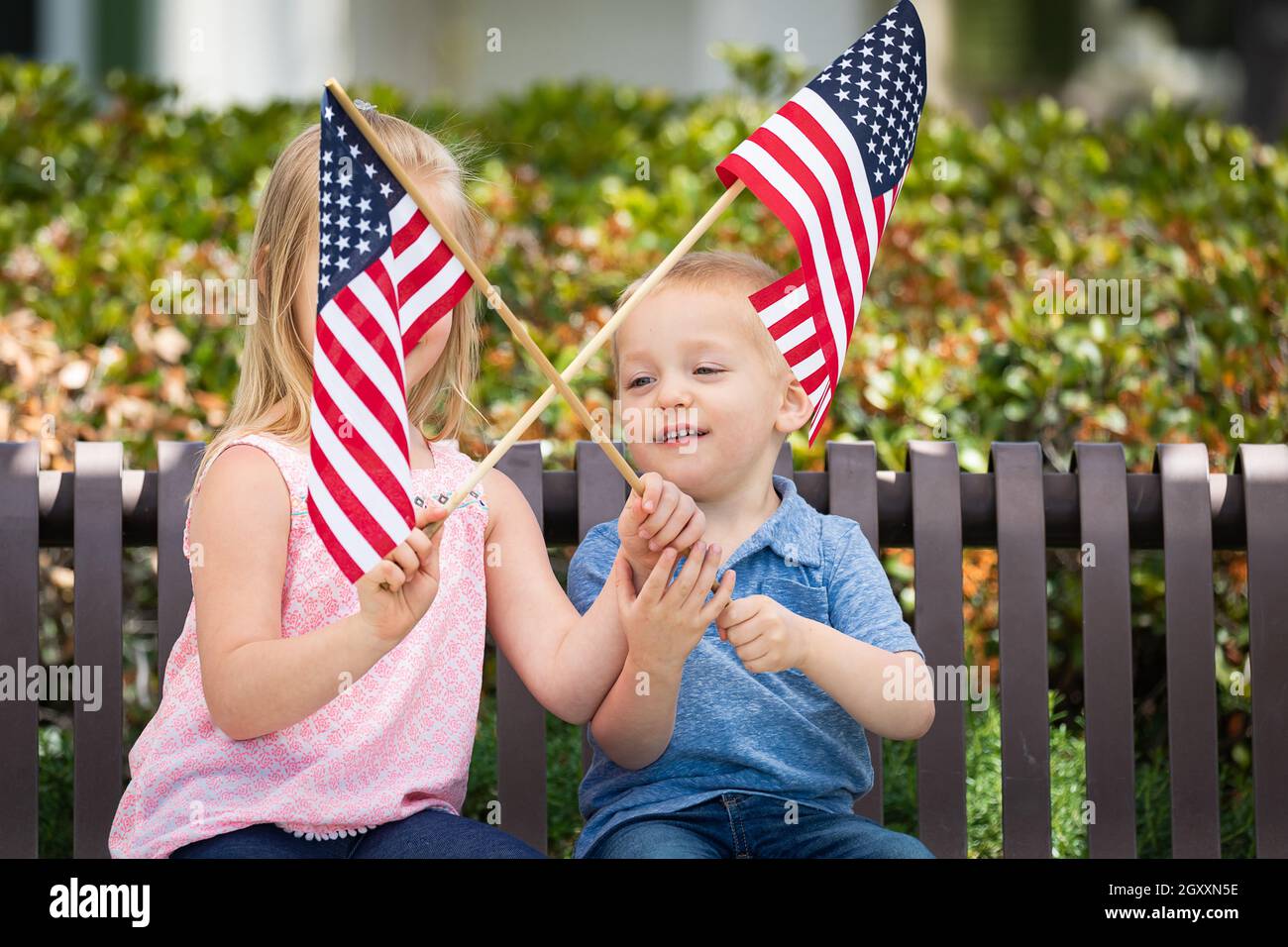 Young Sister and Brother Waving American Flags On The Bench At The Park ...
