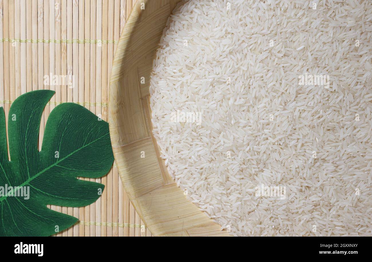 Bowl of Uncooked White Rice with leaf on bamboo mat Stock Photo - Alamy