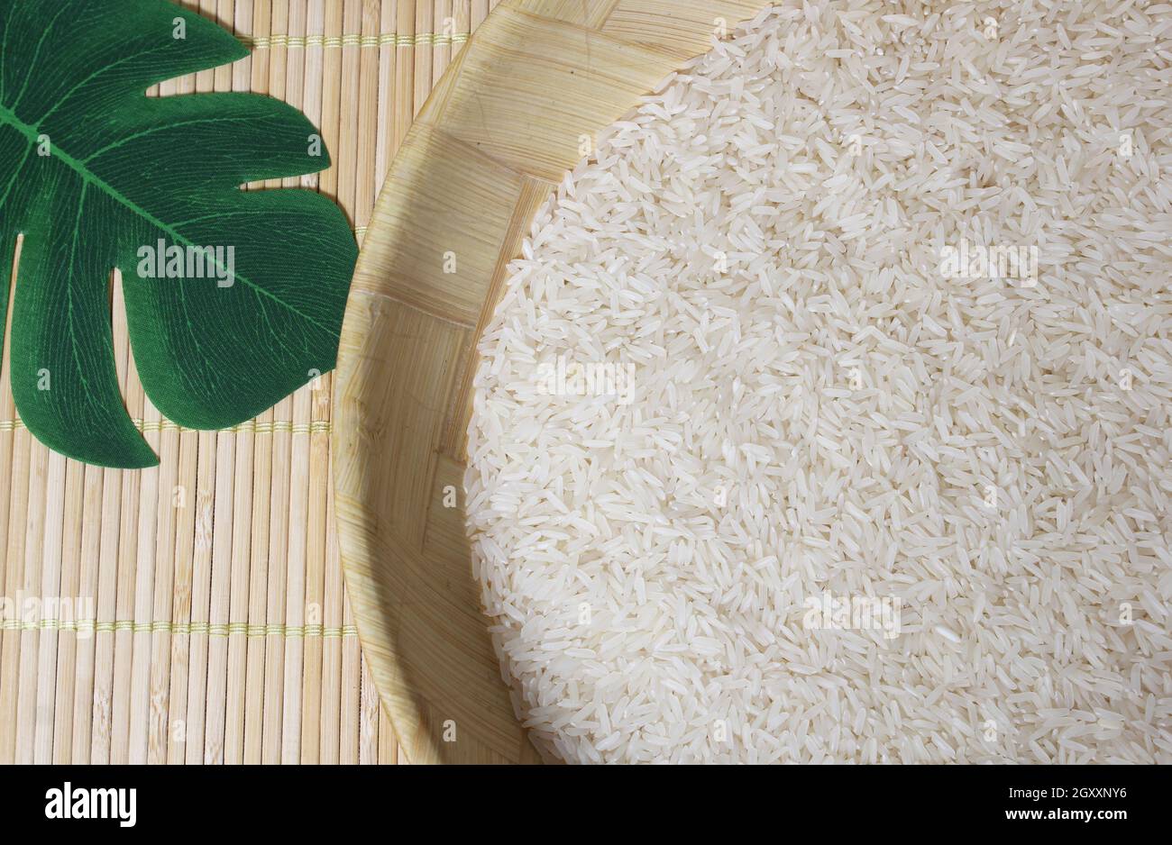 Bowl of Uncooked White Rice with leaf on bamboo mat Stock Photo - Alamy