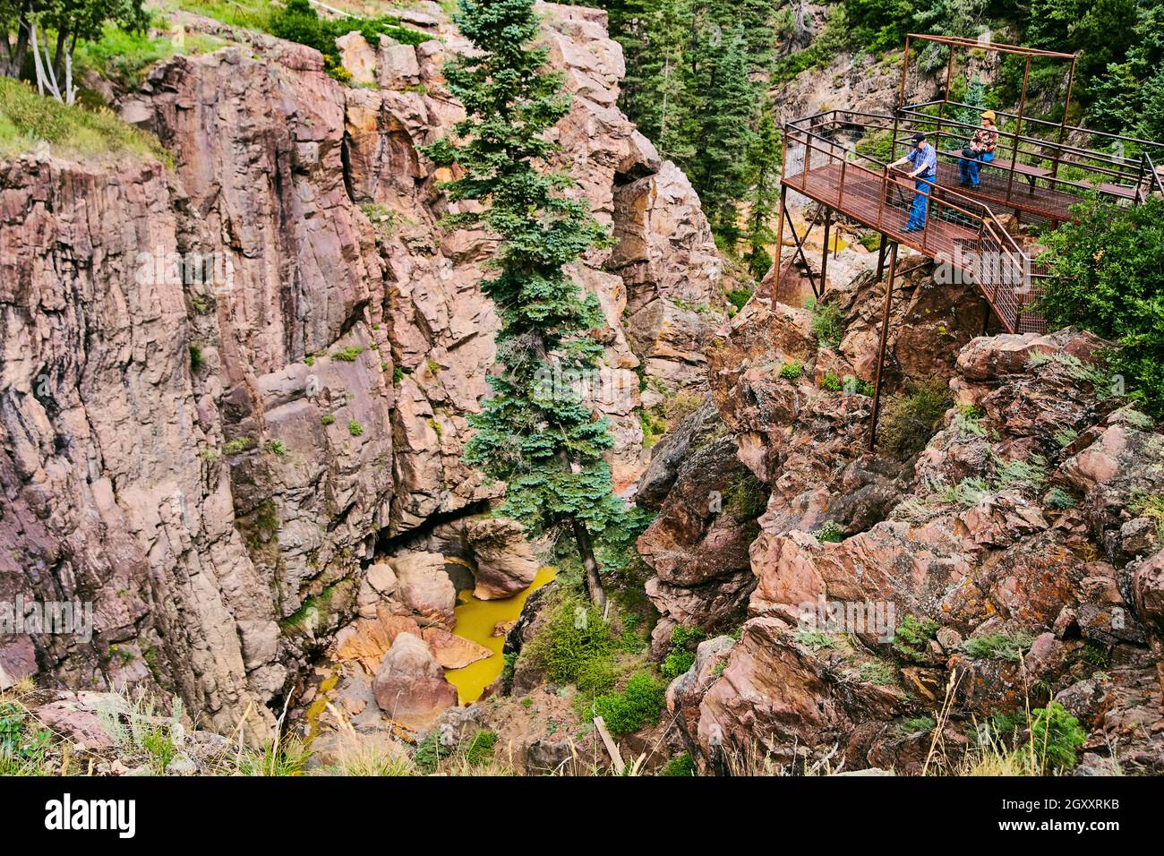 Metal walkway overlooking large gorge in mountains with yellow river ...