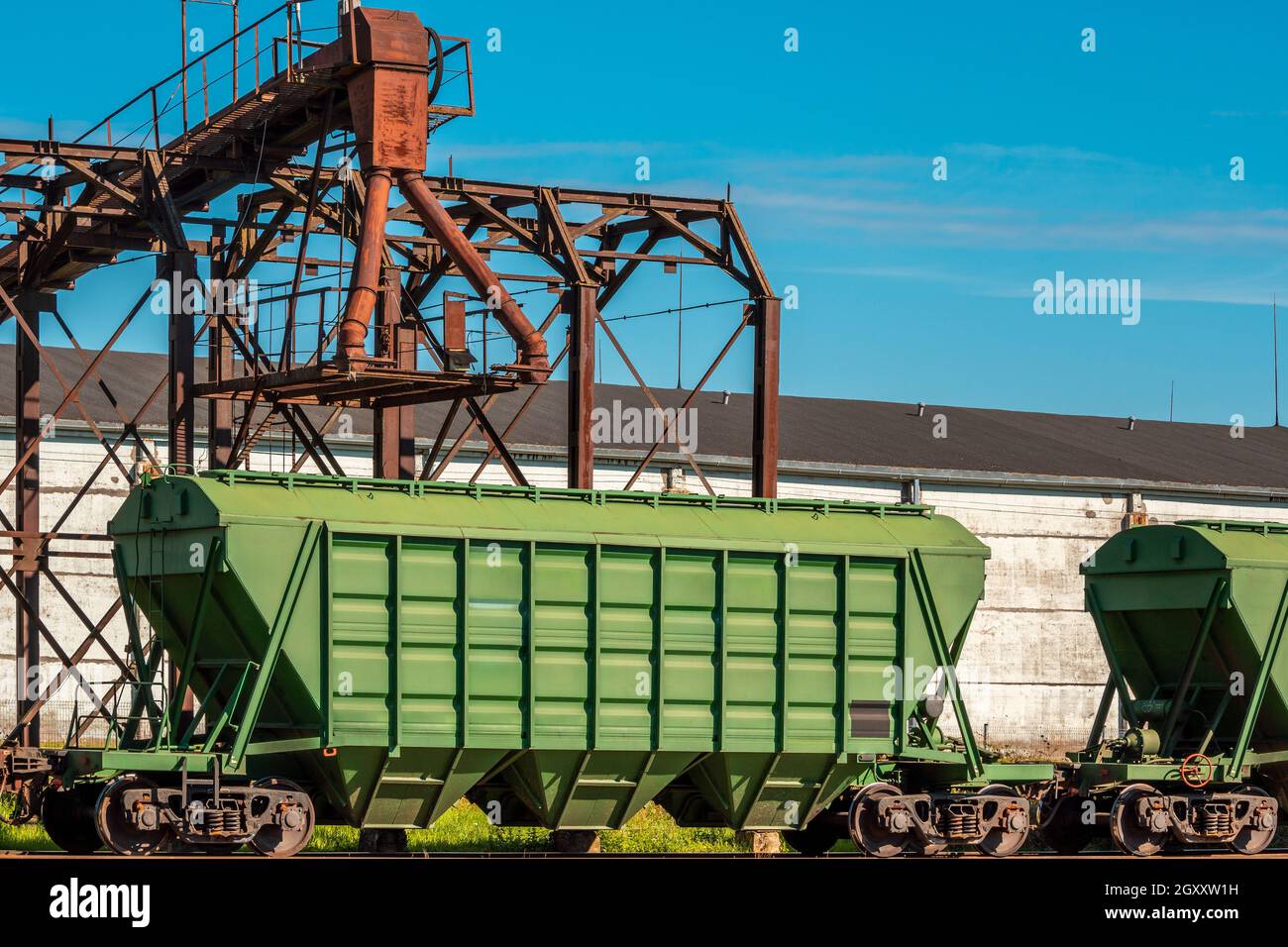 Green loading railway wagon standing near the elevator. Grain silo ...