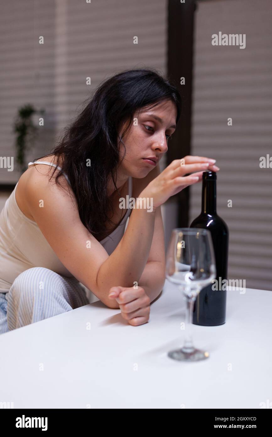 Young adult drinking wine alone in kitchen at home. Heartbroken woman ...