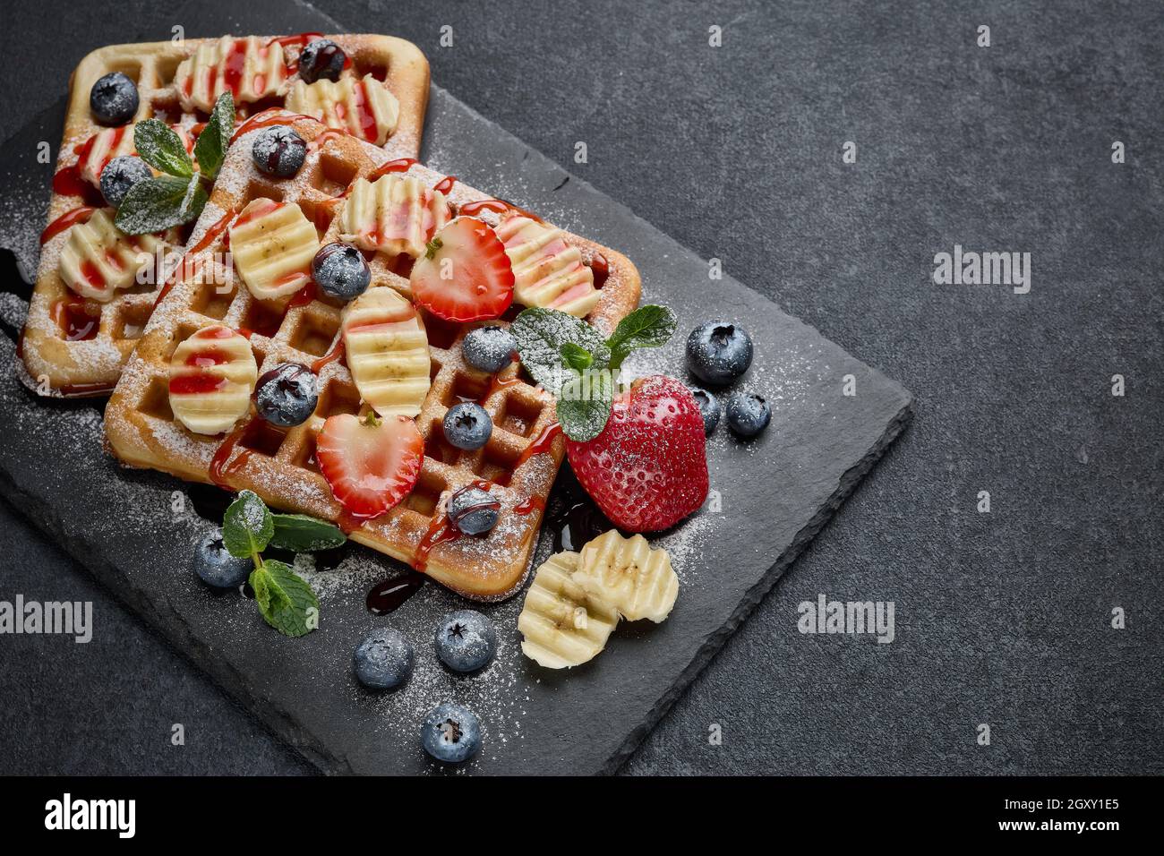 Delicious waffles with berries, mint, powdered sugar and sweet sauce on ...