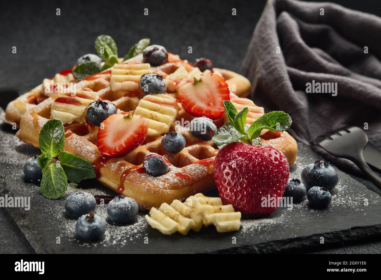 Delicious waffles with berries, mint, powdered sugar and sweet sauce on ...