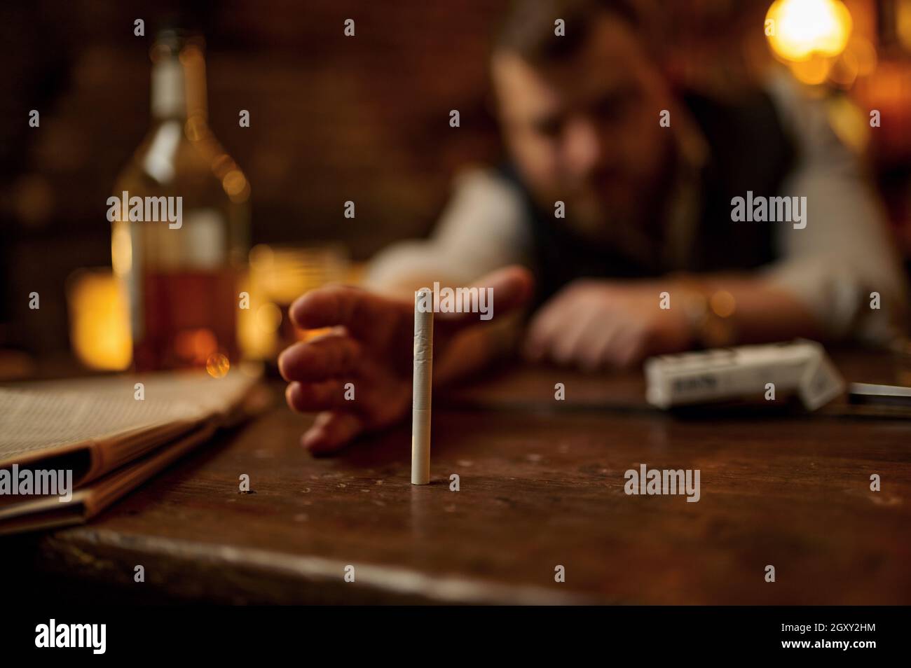 Drunk man tries to take a cigarette, alcohol beverage in bottle on ...