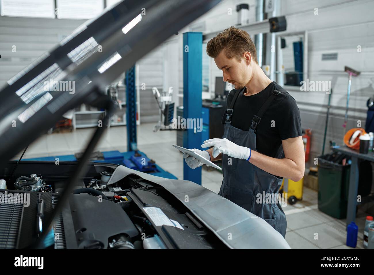 Male worker with checklist stands at the hood, car service. Vehicle ...
