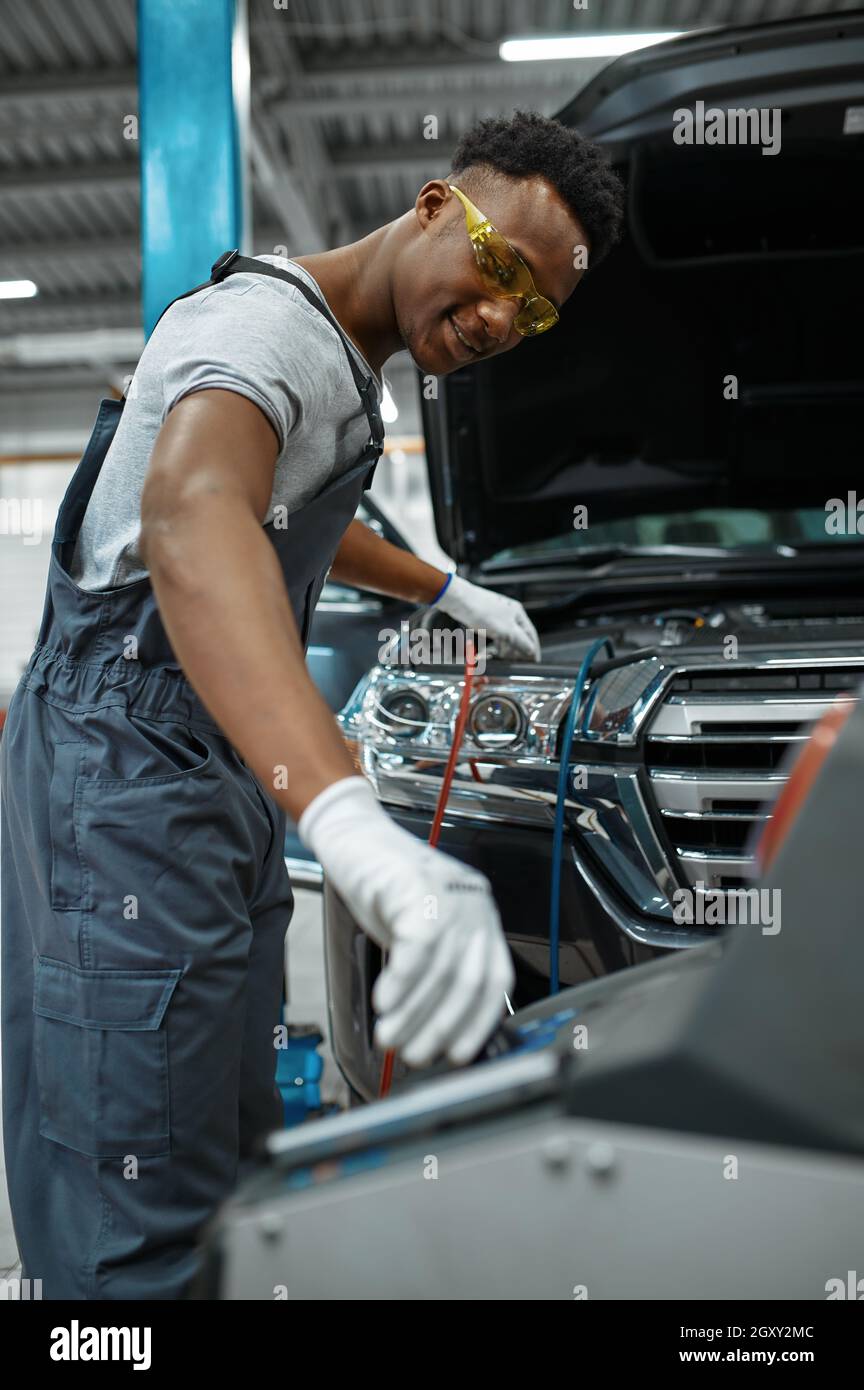 Male worker refills the air conditioner, car service. Vehicle repairing ...