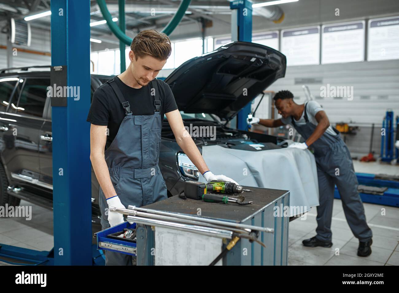 Two male mechanics inspects engine, car service. Vehicle repairing ...