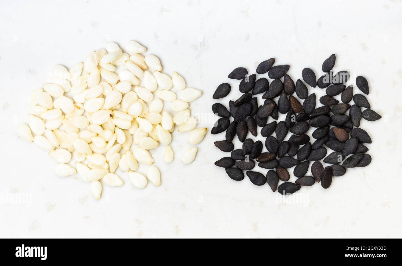 top view of black and white sesame seeds close up on gray ceramic plate ...