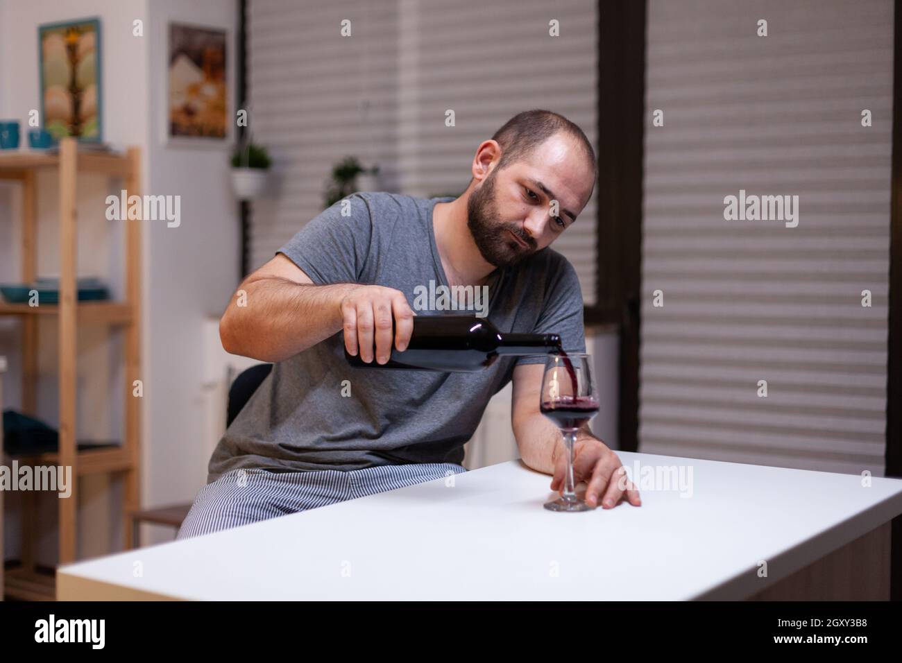 Lonely man pouring wine in glass from bottle drinking alone feeling ...