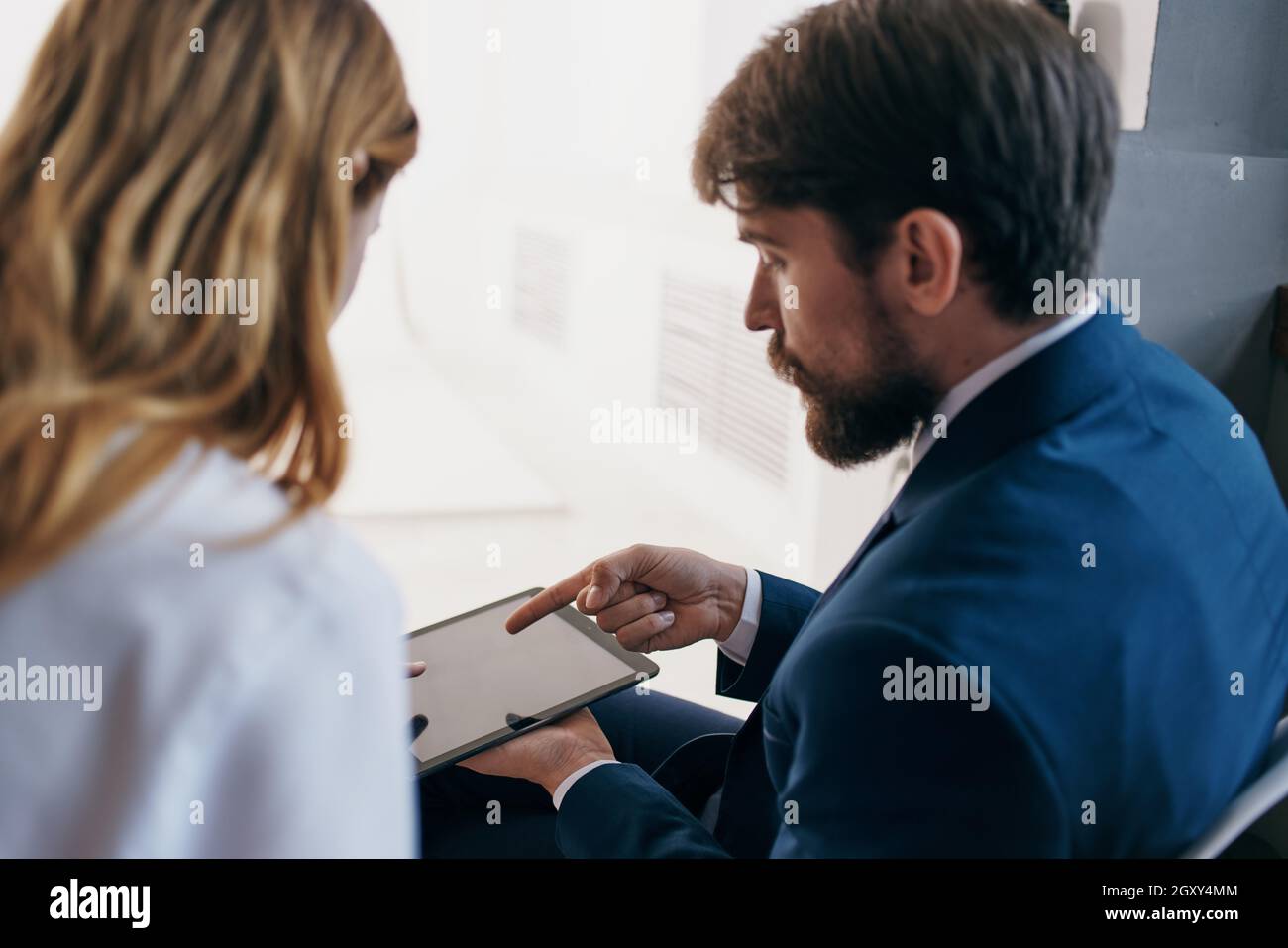 man and woman in business suits communicate with the tablet officials ...