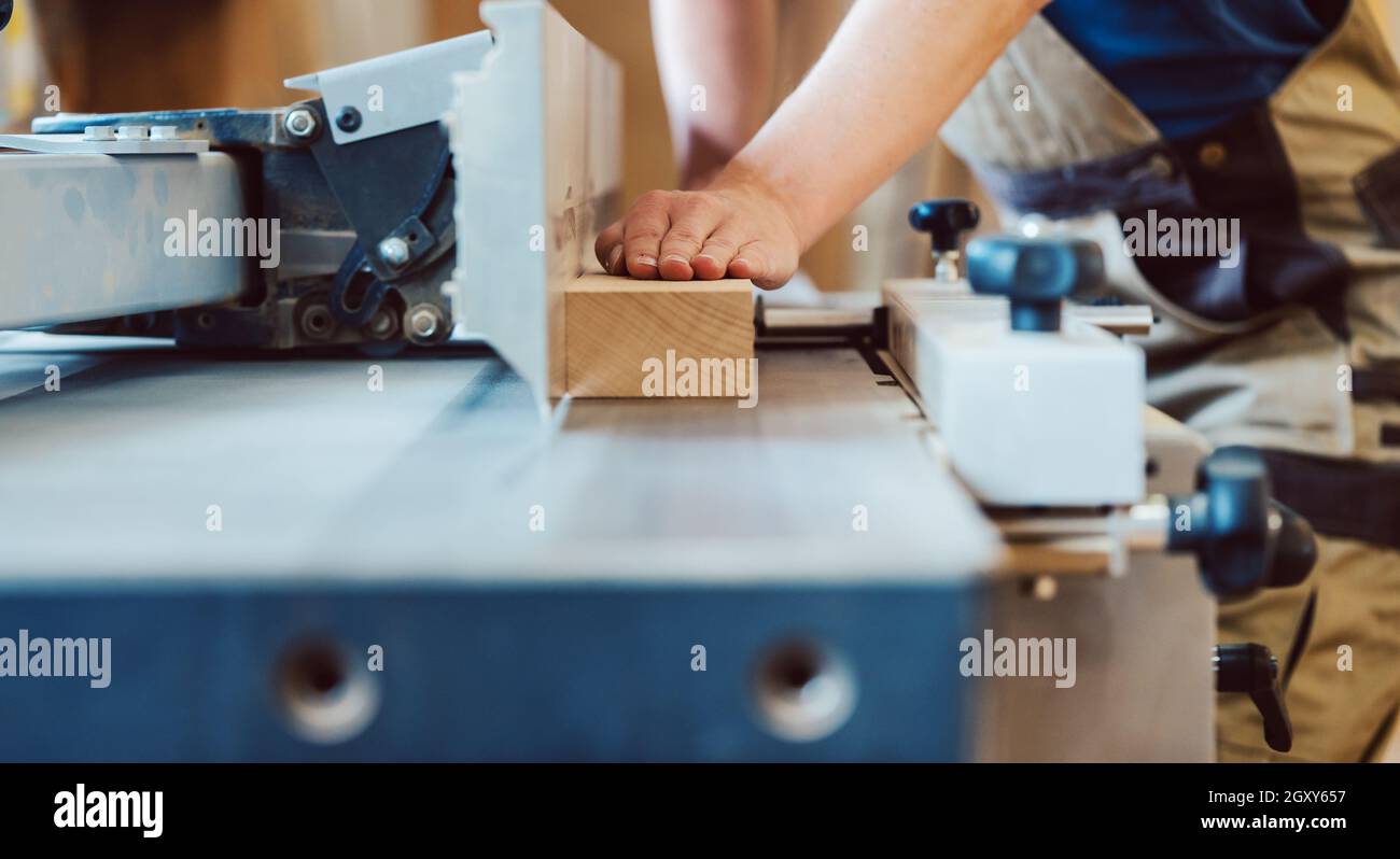 Closeup of carpenter woman at circular cutter working on a wooden plank ...