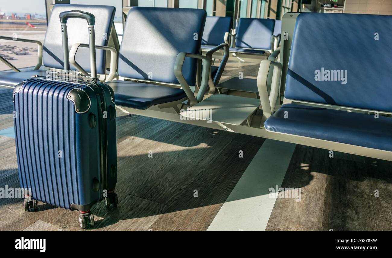 Small plastic travel suitcase in the airport hall Stock Photo - Alamy