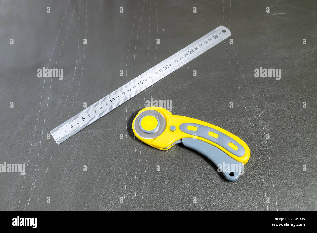 steel ruler and rotary cutter on surface of leather with drawn pattern ...