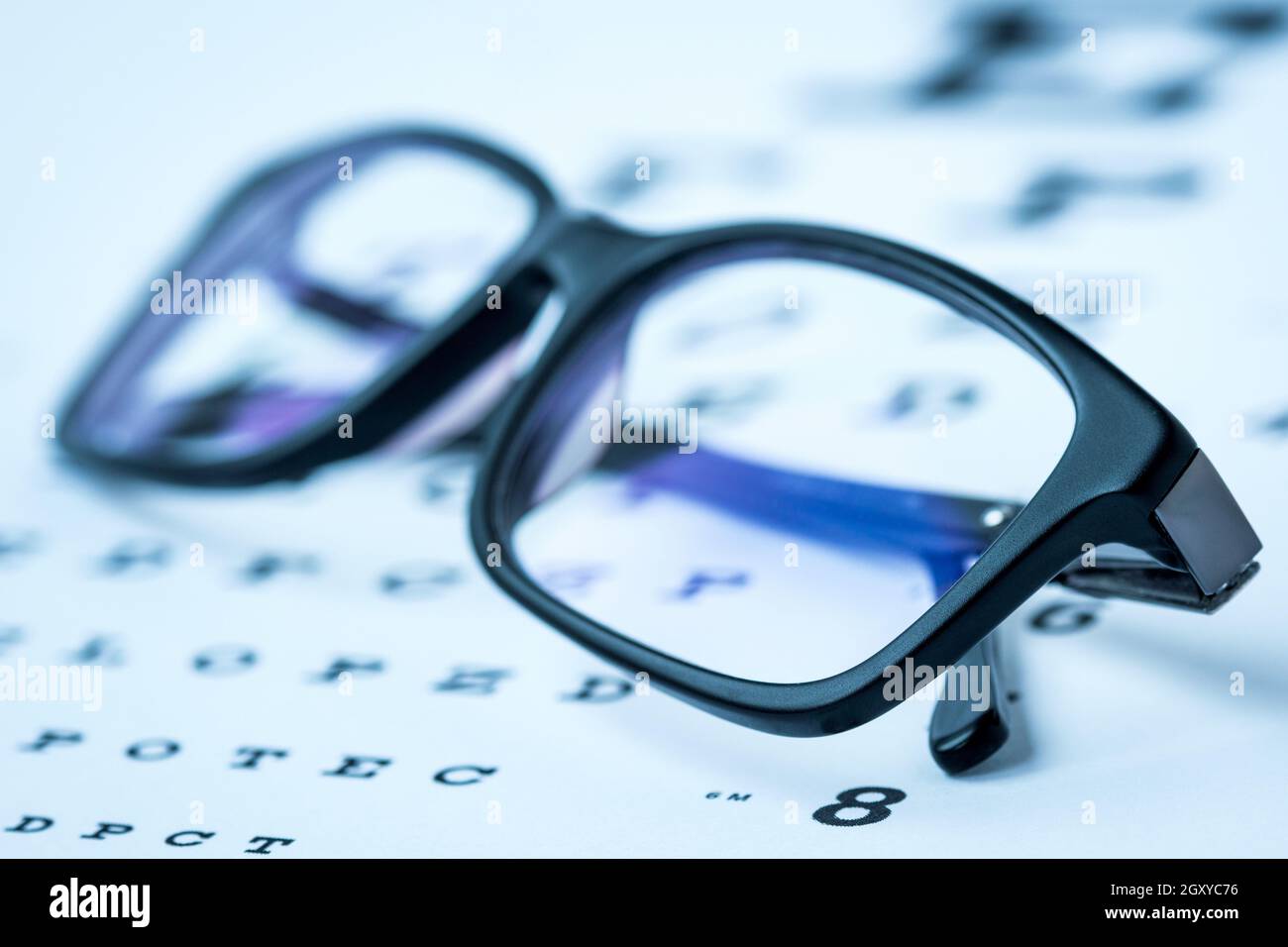 Modern reading glasses on a eye sight test chart. Blue toned image ...