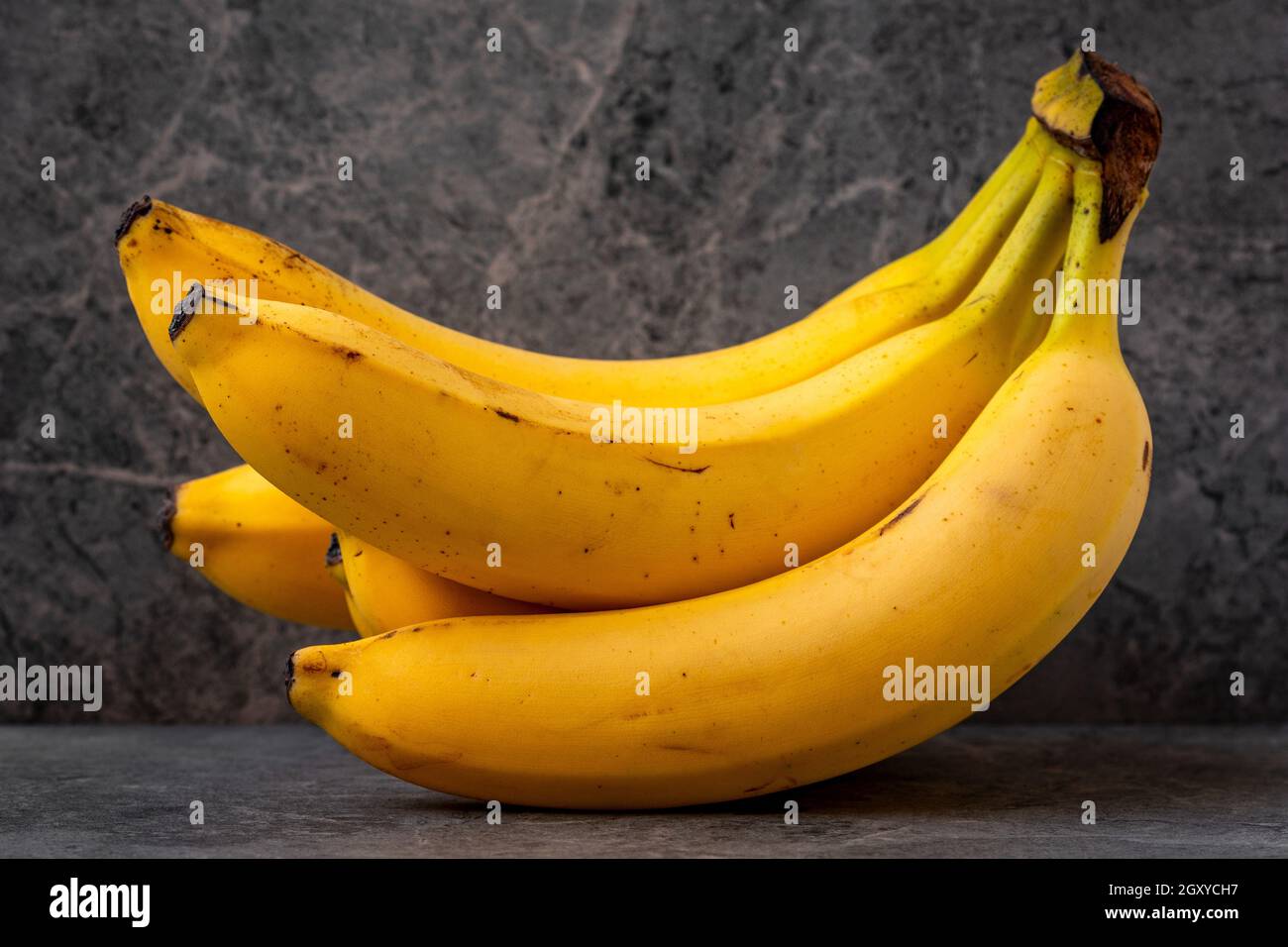 Ripe yellow bananas on grey stone background. Banana fruits are a great ...