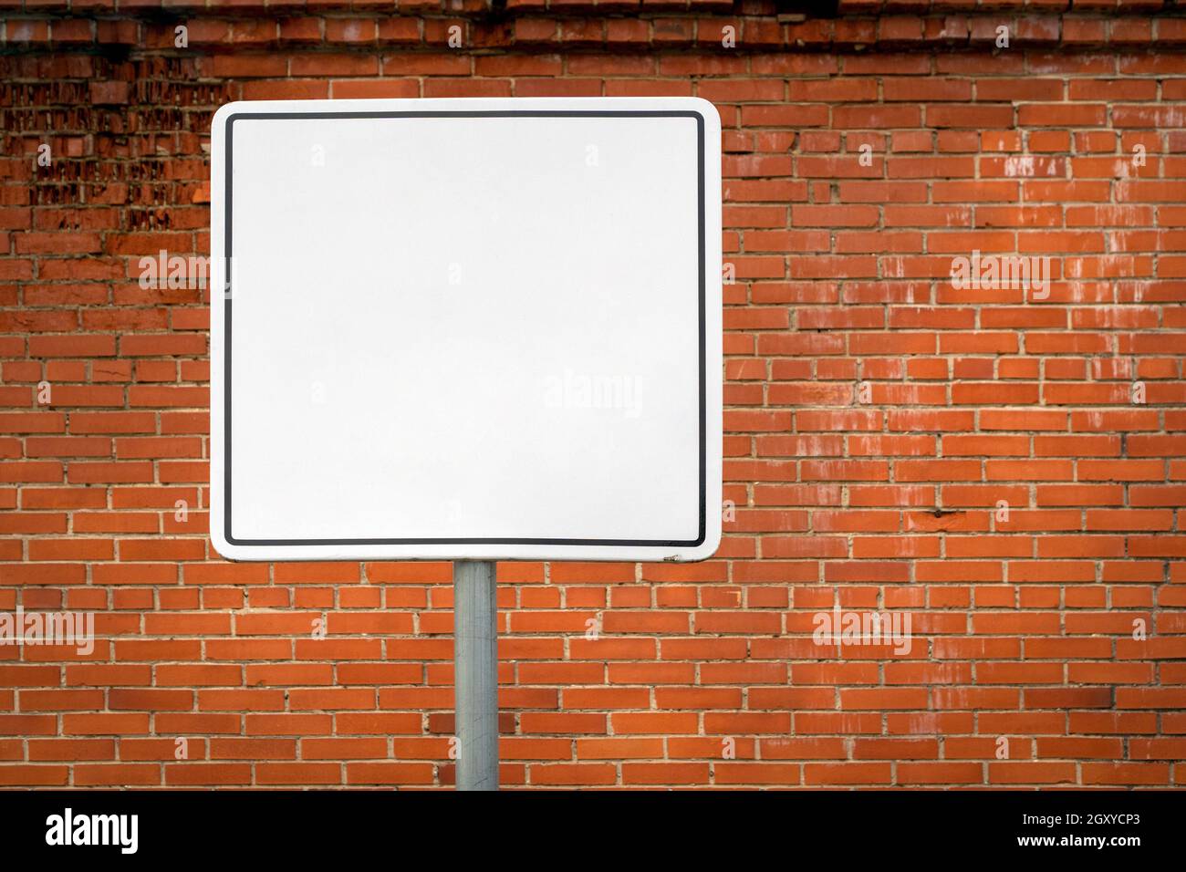 Blank signpost against the brick wall. Empty rectangular frame for text ...
